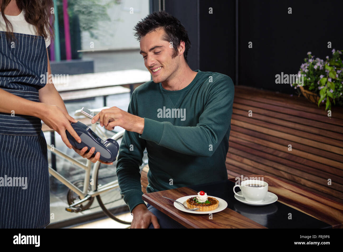 Smiling client paying order with smartphone Stock Photo - Alamy