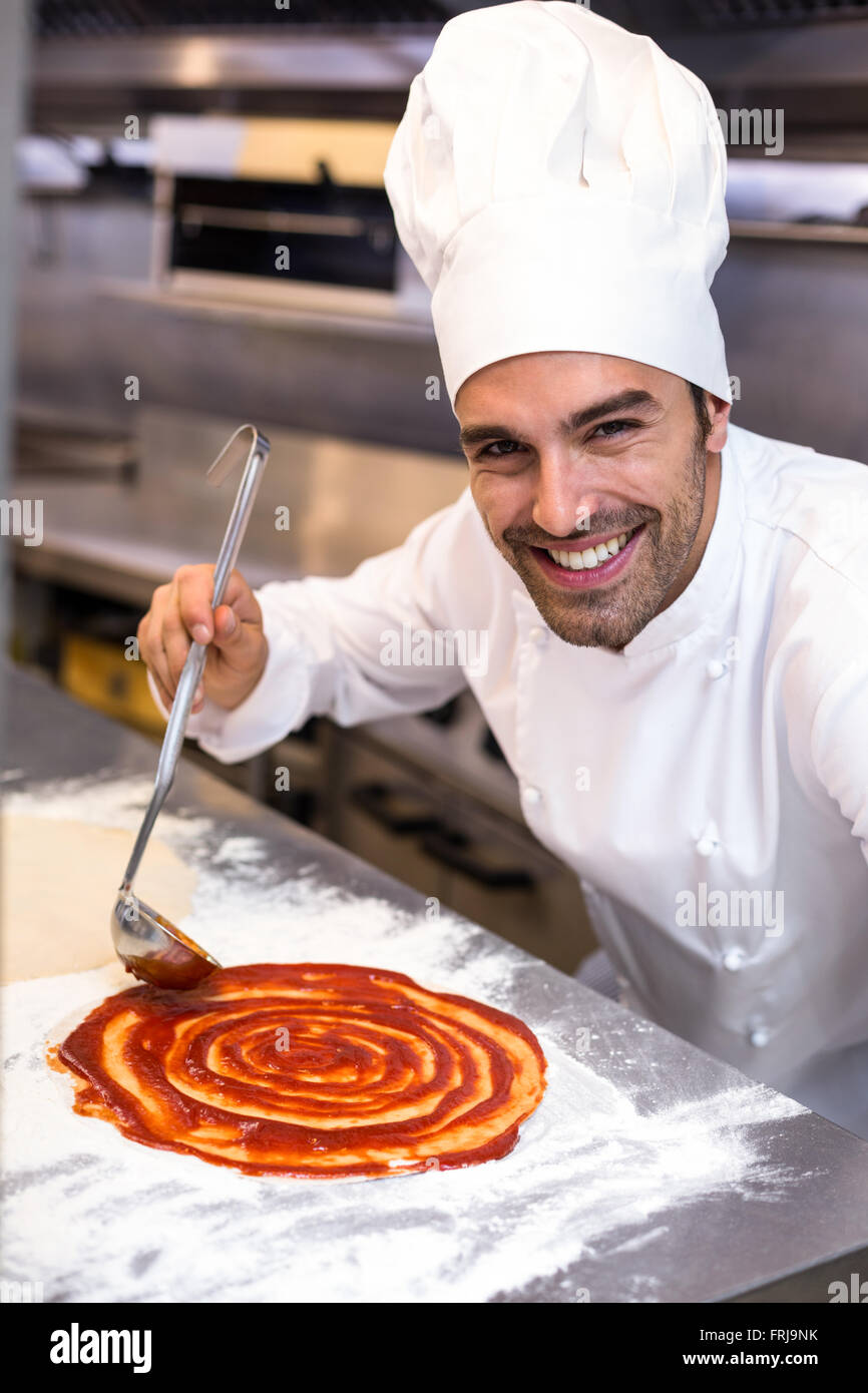 Pizza chef put sauce on base Stock Photo - Alamy