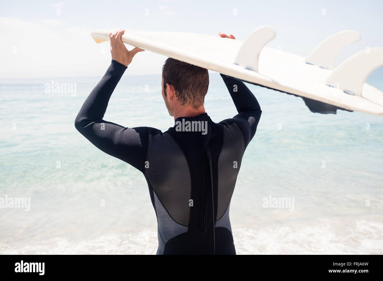 Rear view of surfer holding surfboard over head Stock Photo - Alamy