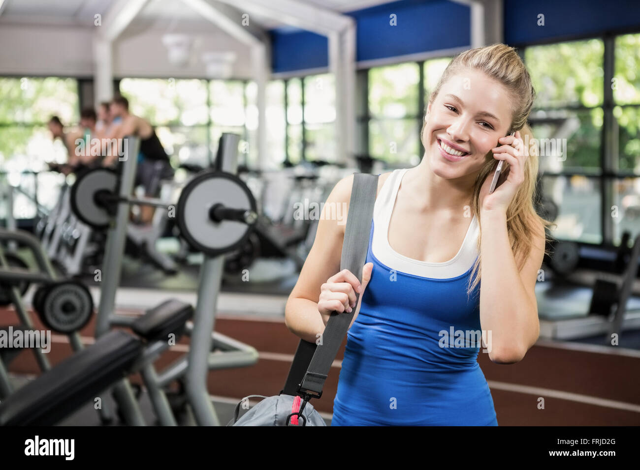 Woman with gym bag talking on the phone in weights room Stock Photo - Alamy