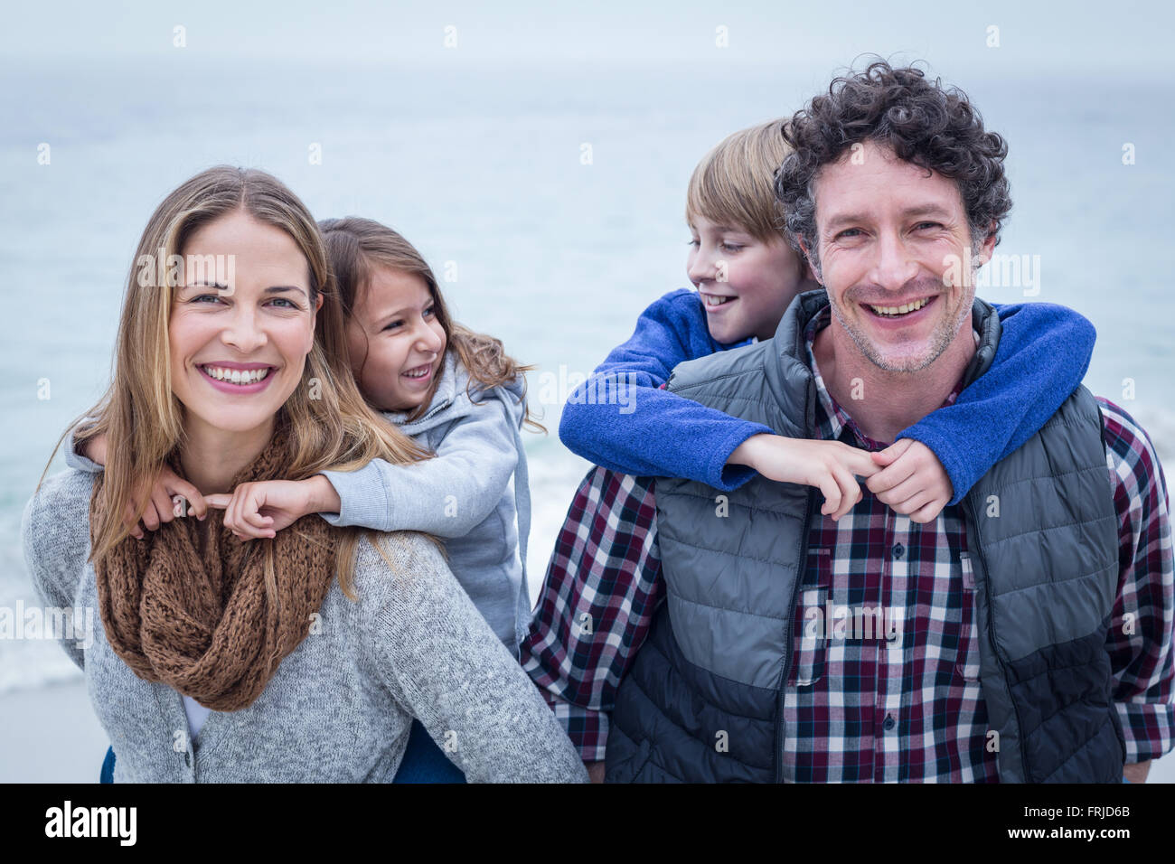 Cheerful parents carrying children on back at beach Stock Photo - Alamy