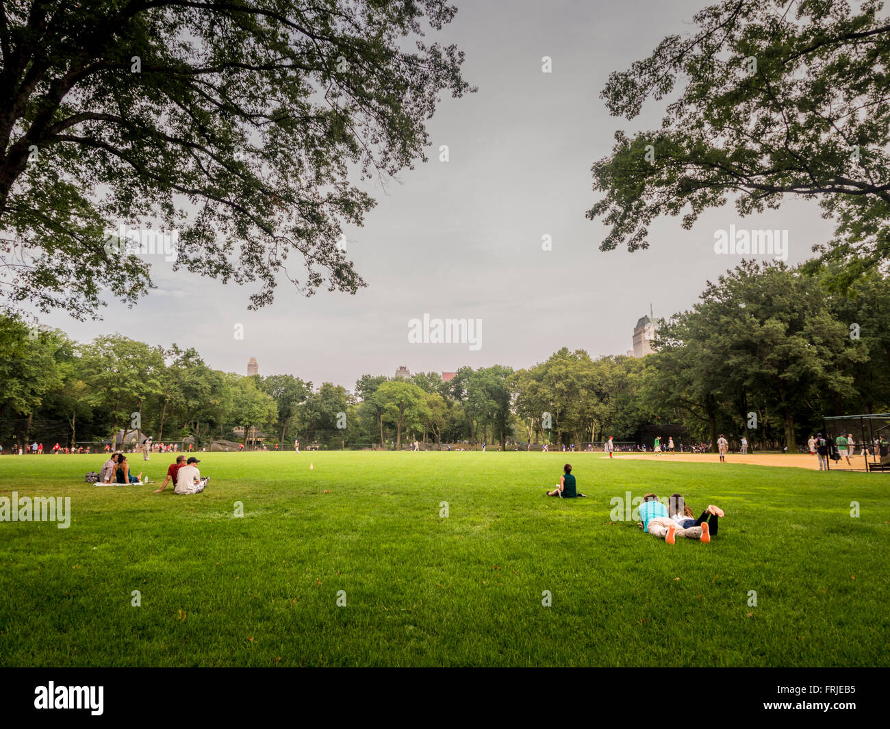 Spectators lying and sitting on grass watching Baseball game, Central ...