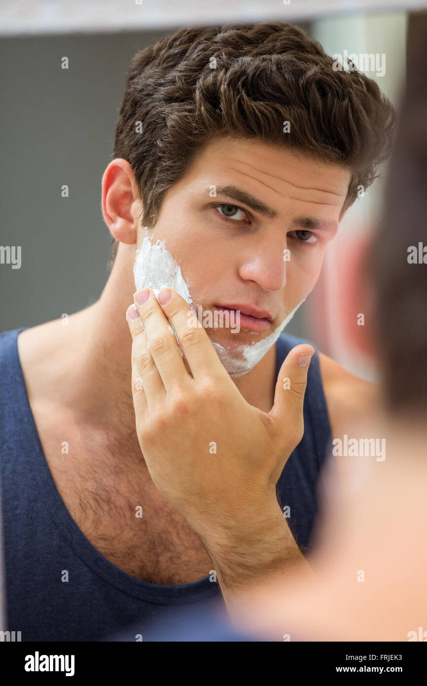 Young man applying shaving foam on his face Stock Photo - Alamy