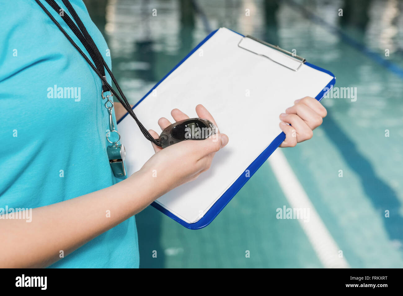 Mid section of coach with a stop watch and clipboard by pool Stock ...