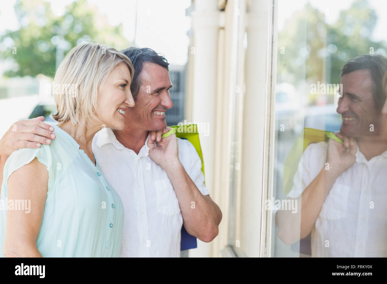 Happy couple looking at reflection Stock Photo - Alamy