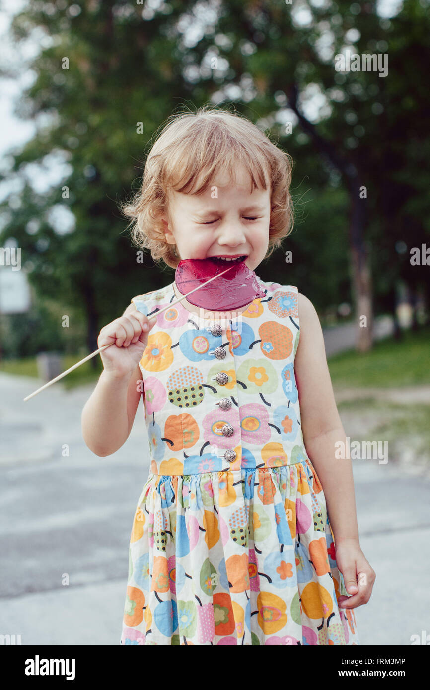 Little girl eats candy on stick Stock Photo - Alamy