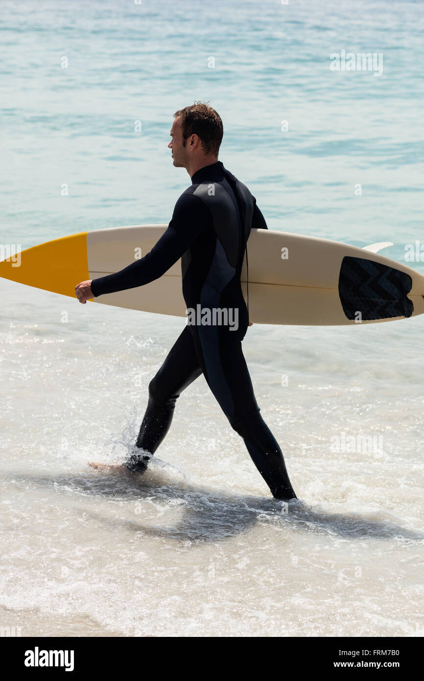 Surfer walking on the beach with a surfboard Stock Photo - Alamy
