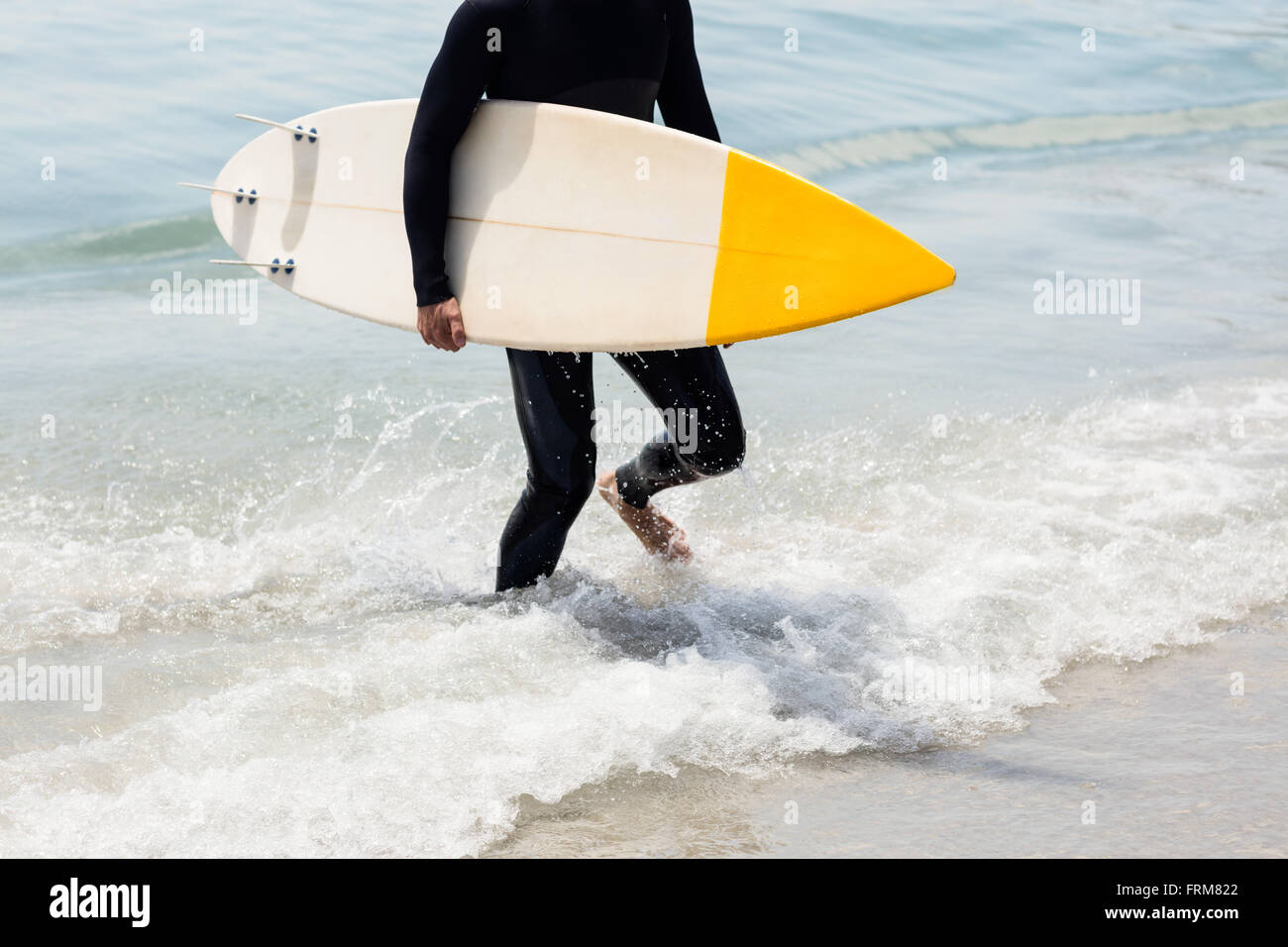 Surfer walking on the beach with a surfboard Stock Photo - Alamy