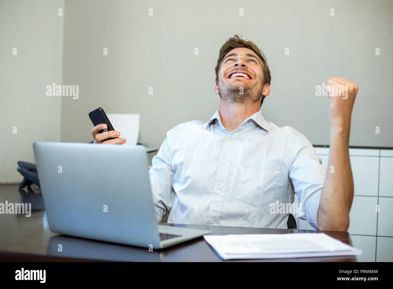 Smiling happy man holding mobile phone in office Stock Photo - Alamy