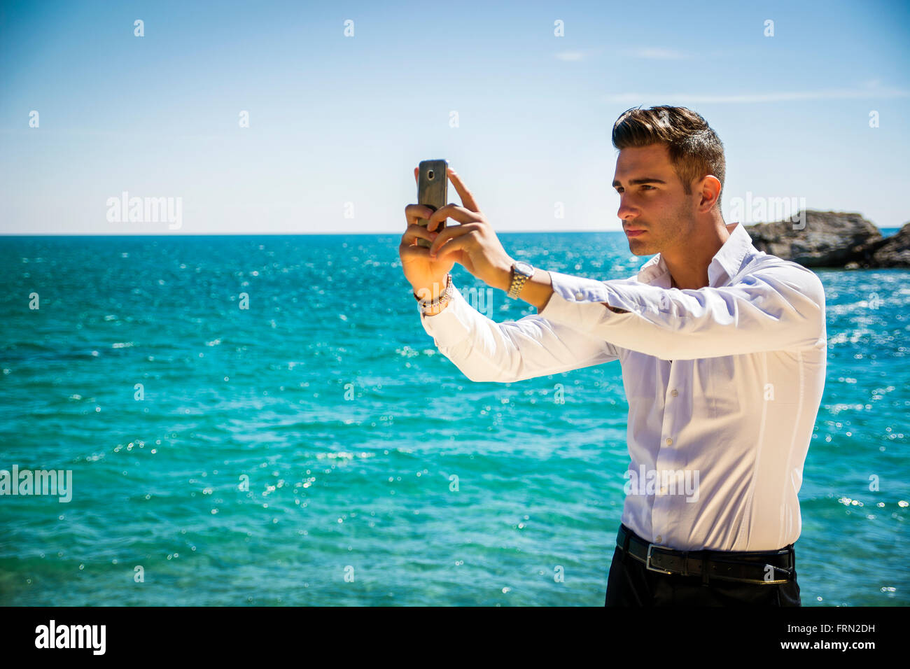 Side View of a Elegant Young Man Taking Selfie Photos at the Beach ...