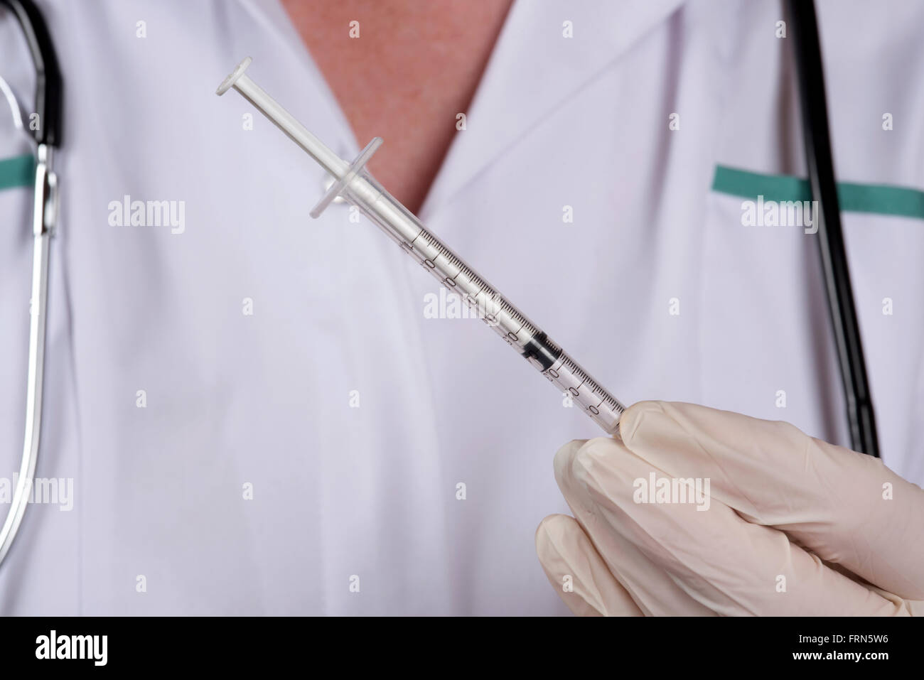 A disposable plastic sterile syringe being held in a woman's surgical ...