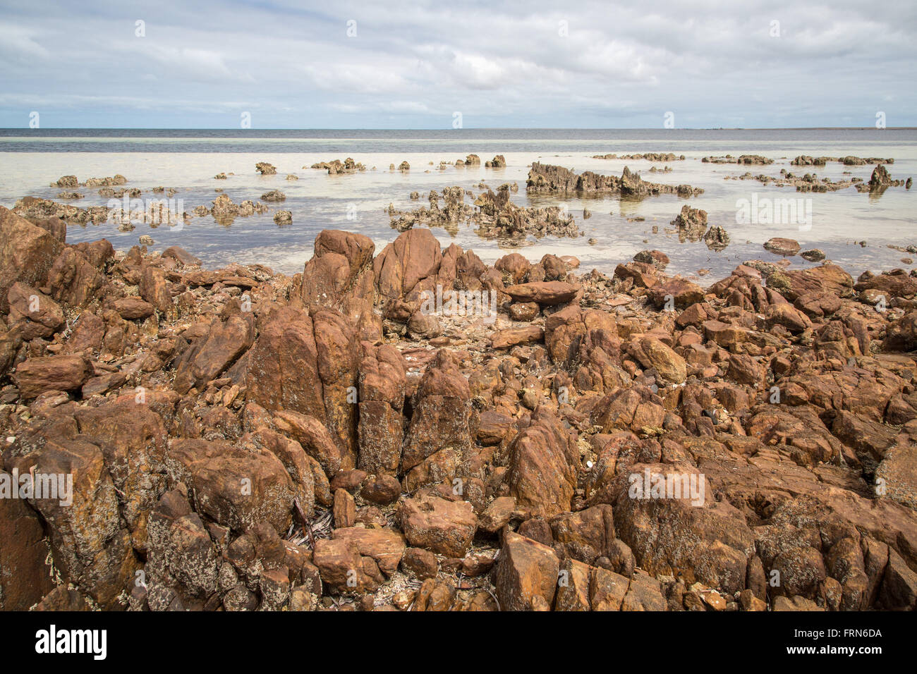 rocky beach, light sands in shallow water, horizon, slightly hazy ...