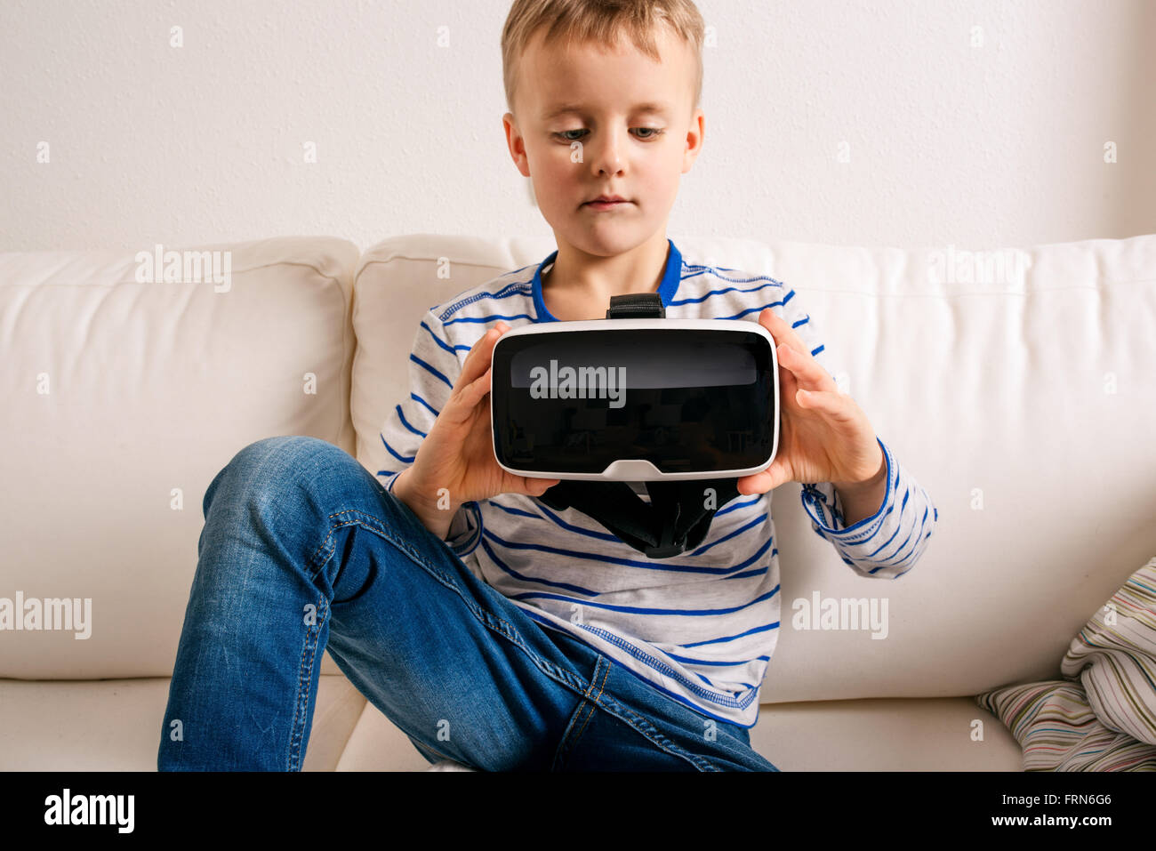 Boy with virtual reality goggles. Studio shot, white couch Stock Photo ...