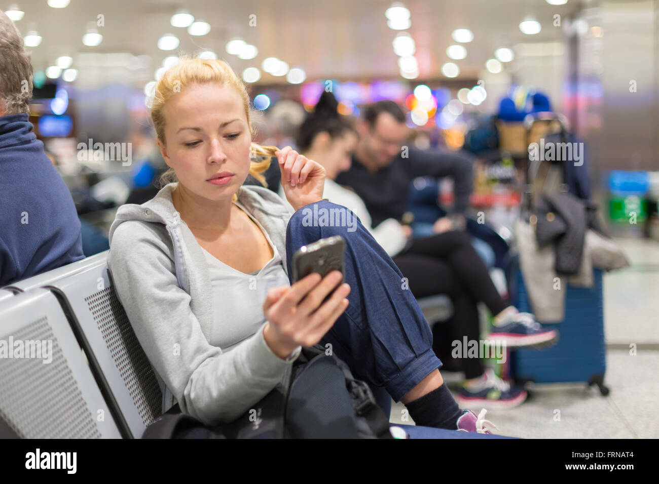 Female traveler using cell phone while waiting Stock Photo - Alamy