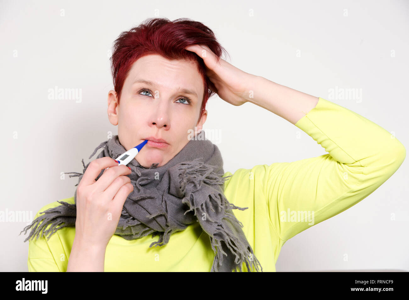 portrait of red-haired woman having a cold and thermometer in her mouth ...