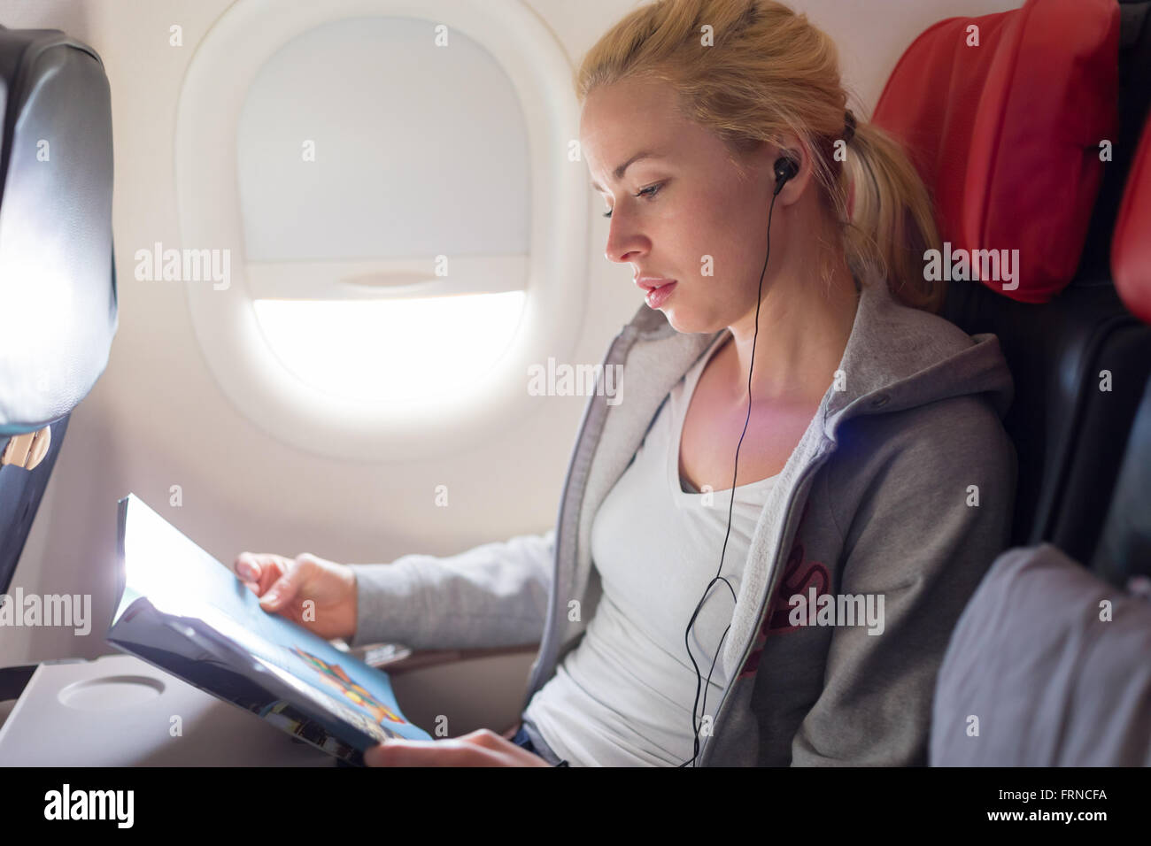 Woman reading magazine on airplane Stock Photo - Alamy