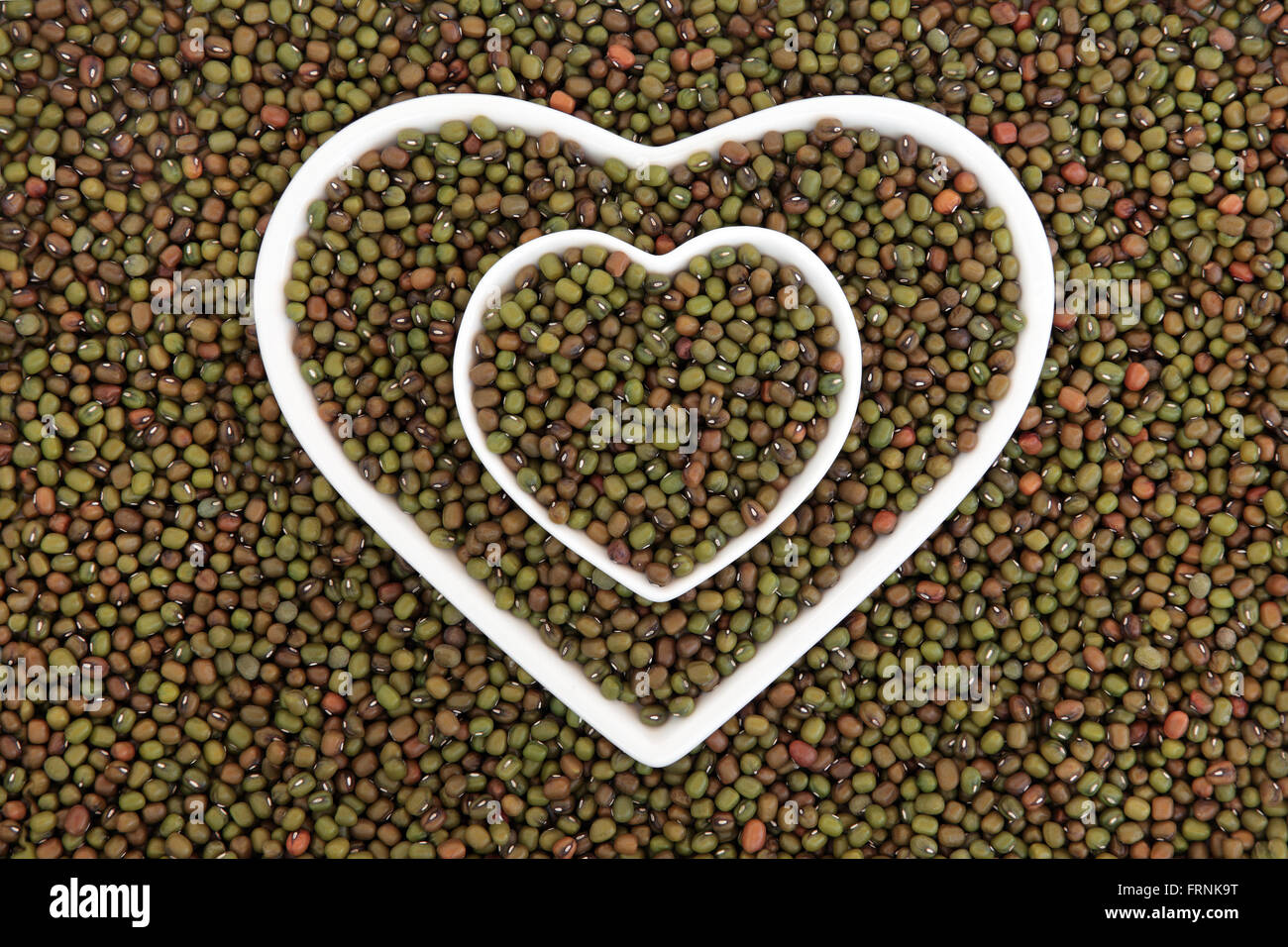 Mung beans in heart shaped porcelain dishes forming an abstract ...