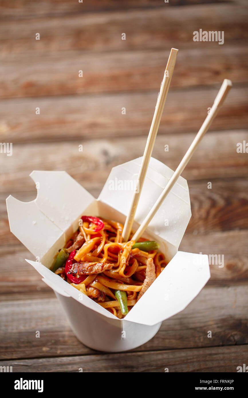 Noodles with pork and vegetables in take-out box on wooden table Stock ...