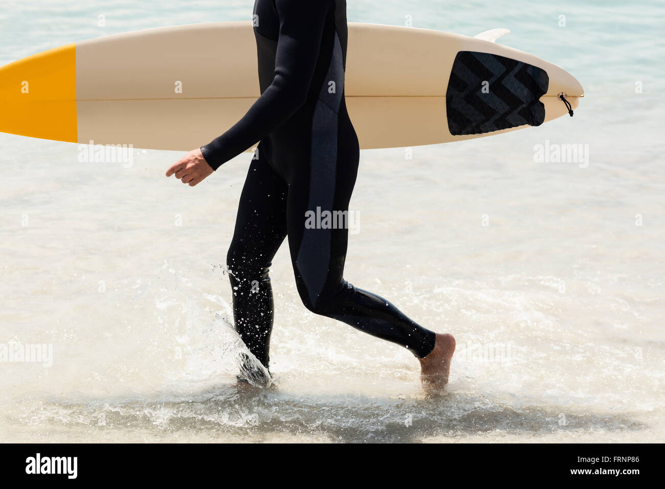 Surfer walking on the beach with a surfboard Stock Photo - Alamy