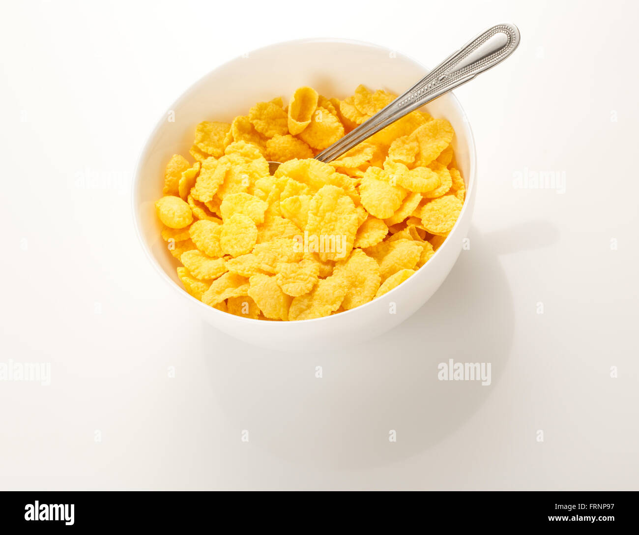 Yellow corn flakes in white bowl with spoon Stock Photo - Alamy