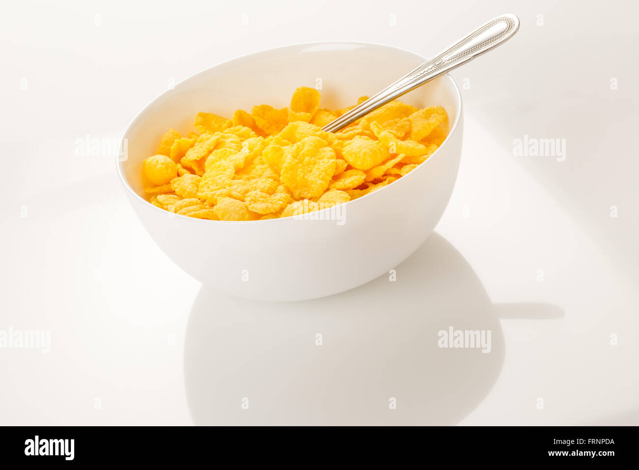 Yellow corn flakes in white bowl with spoon Stock Photo - Alamy