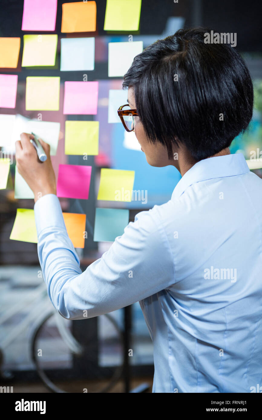 Businesswoman writing on sticky note Stock Photo - Alamy