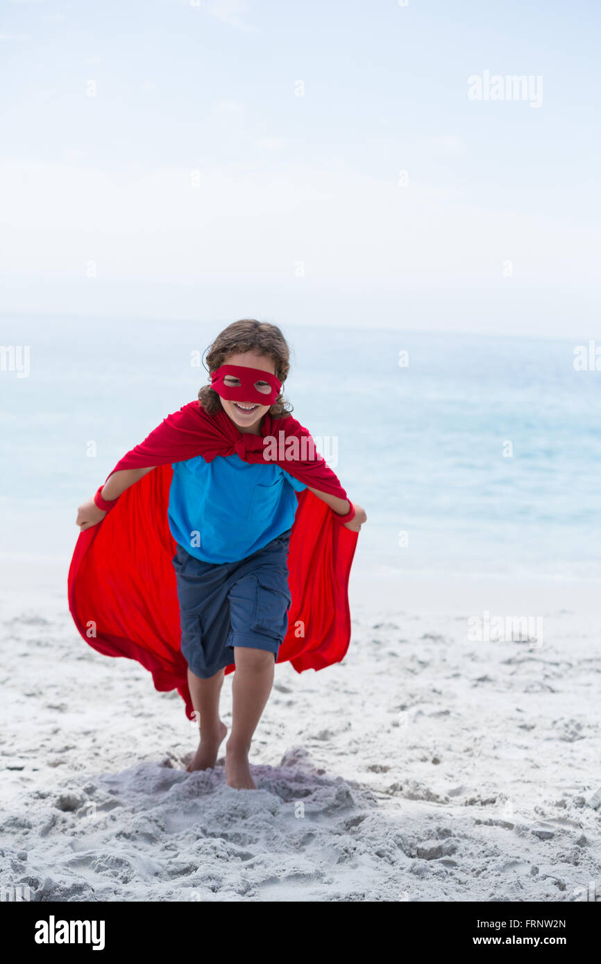 Boy in superhero costume running while holding cape Stock Photo - Alamy