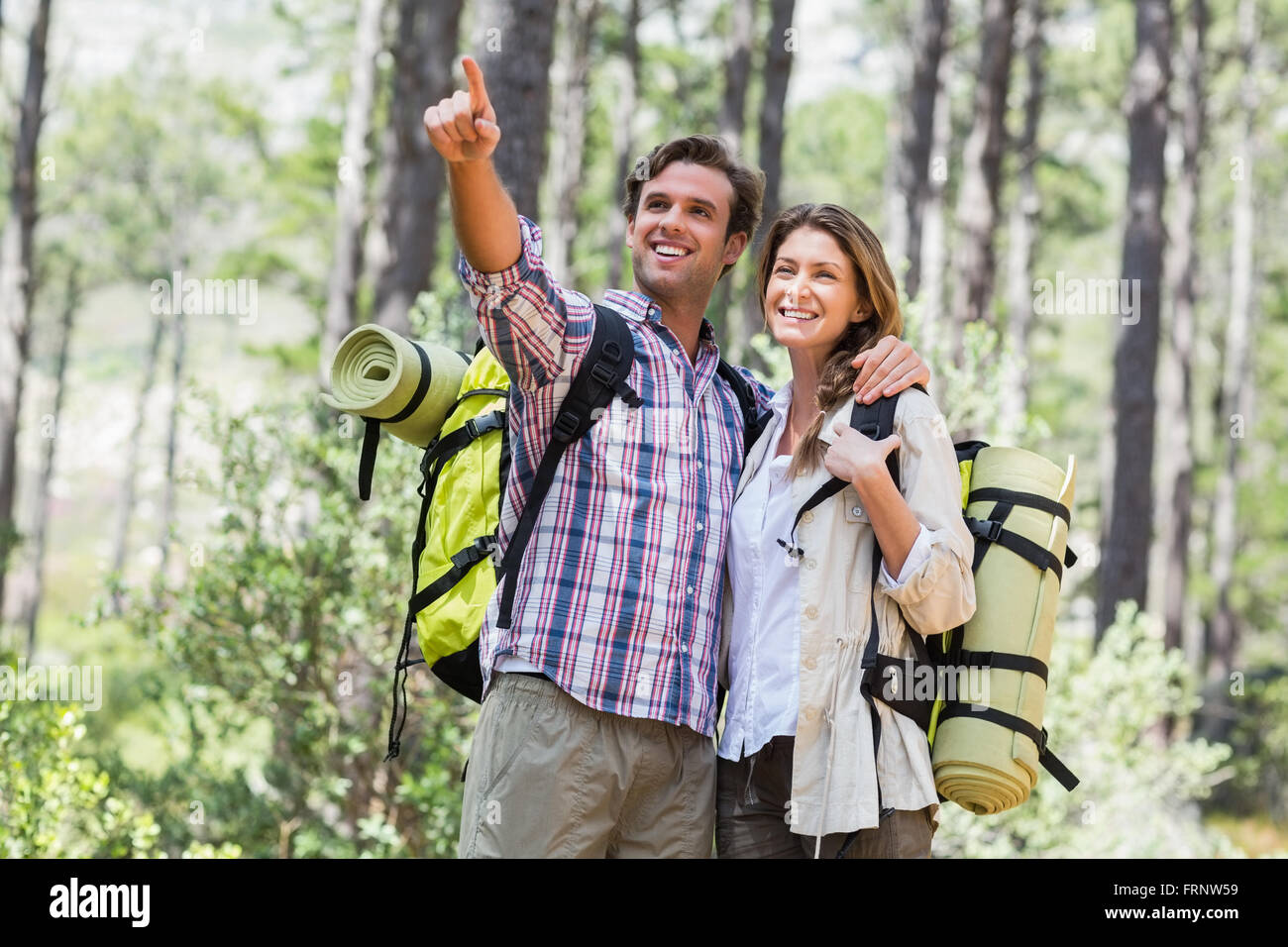 Happy man pointing while standing with partner in forest Stock Photo ...