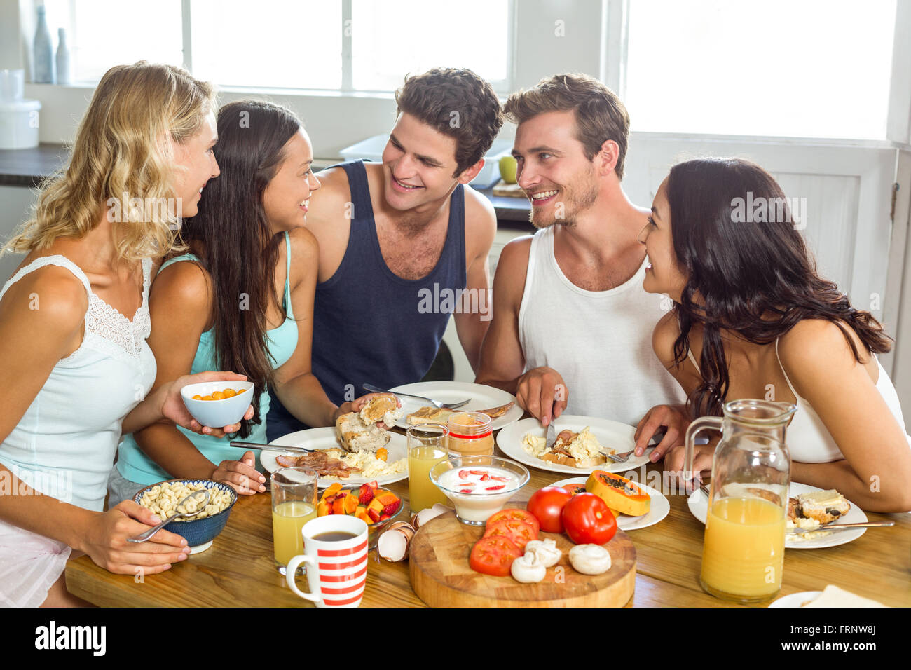 Smiling young friends having breakfast at table in house Stock Photo ...