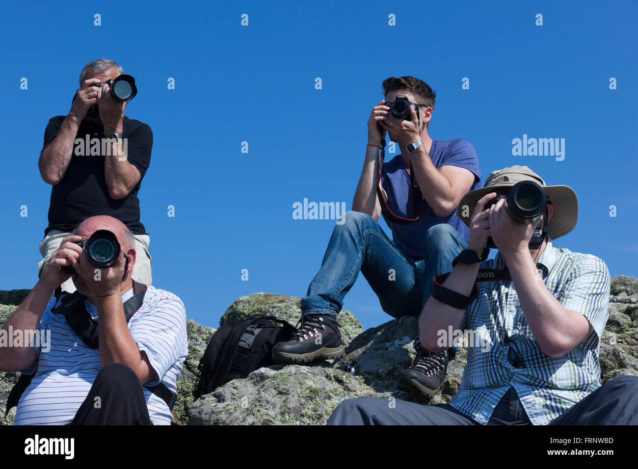 A group of men on a photography course, holding up their cameras and ...