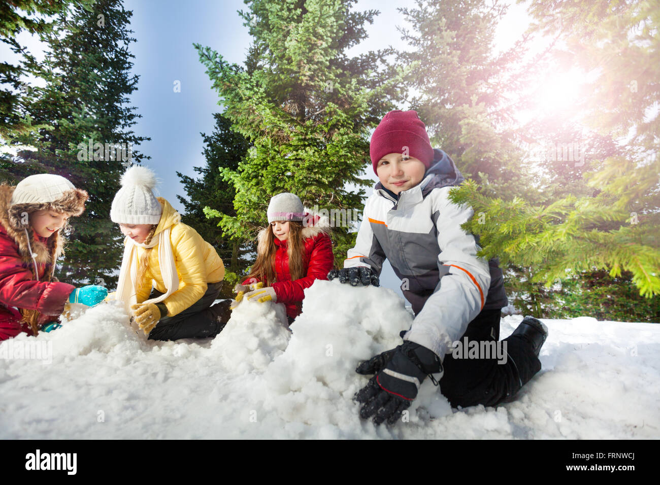 Four kids making snowman at beautiful forest Stock Photo - Alamy