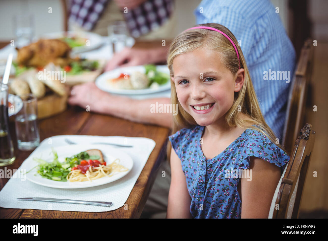 Smiling girl sitting at dining table Stock Photo - Alamy