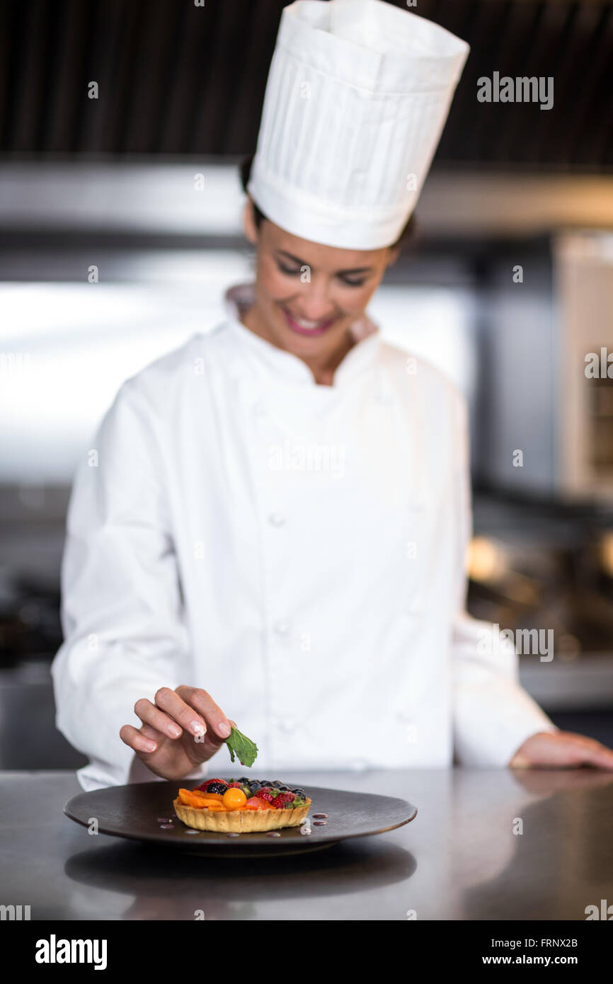 Happy female chef garnishing on food Stock Photo - Alamy