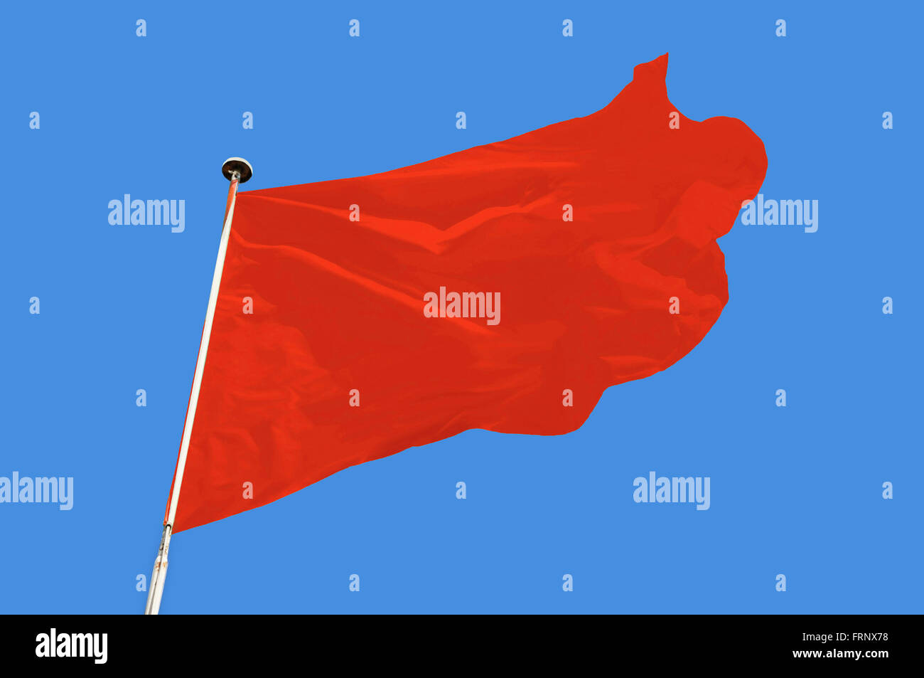 Red flag flying in a stiff breeze against a clear blue sky Stock Photo ...