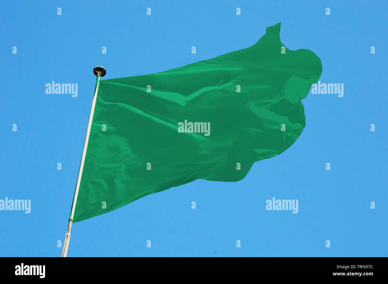 Bright green flag fluttering in a brisk breeze against a bright blue ...