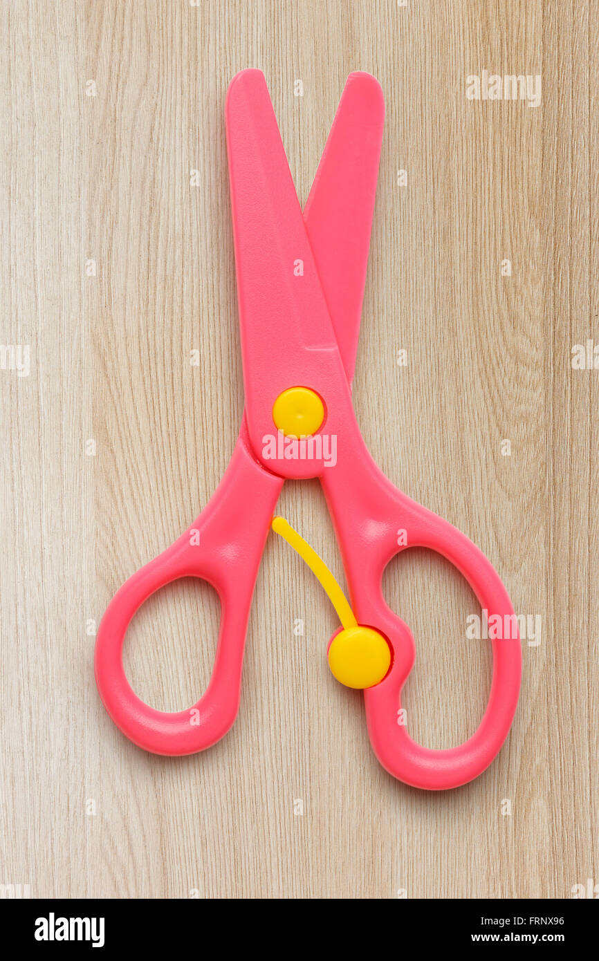 Pink safe children scissors on wooden background Stock Photo - Alamy