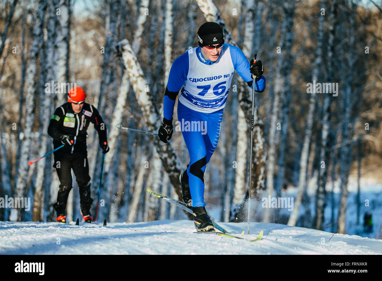 rivalry men skiers race classic style in a birch forest in winter ...