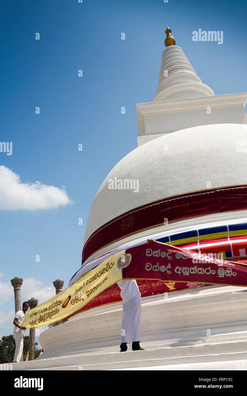 Sri Lanka, Anuradhapura, Thuparamaya Dagoba, men draping banner around ...