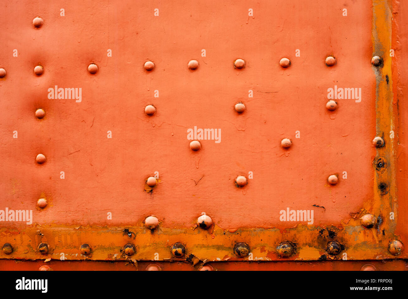 Old faded red metal background with a random pattern of studs ...