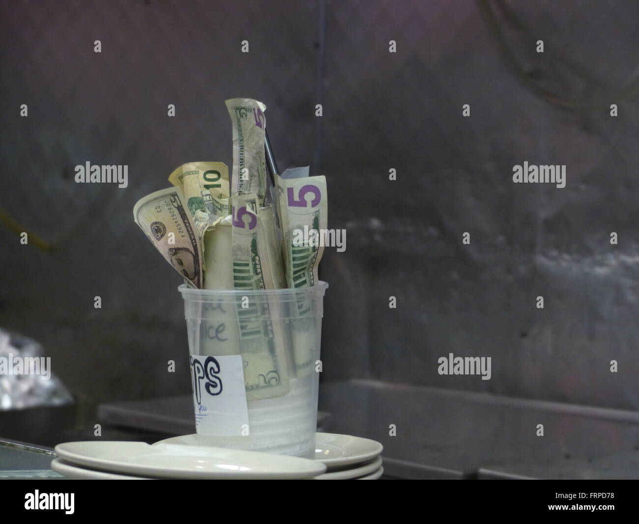 Cash tips in plastic cup Stock Photo - Alamy