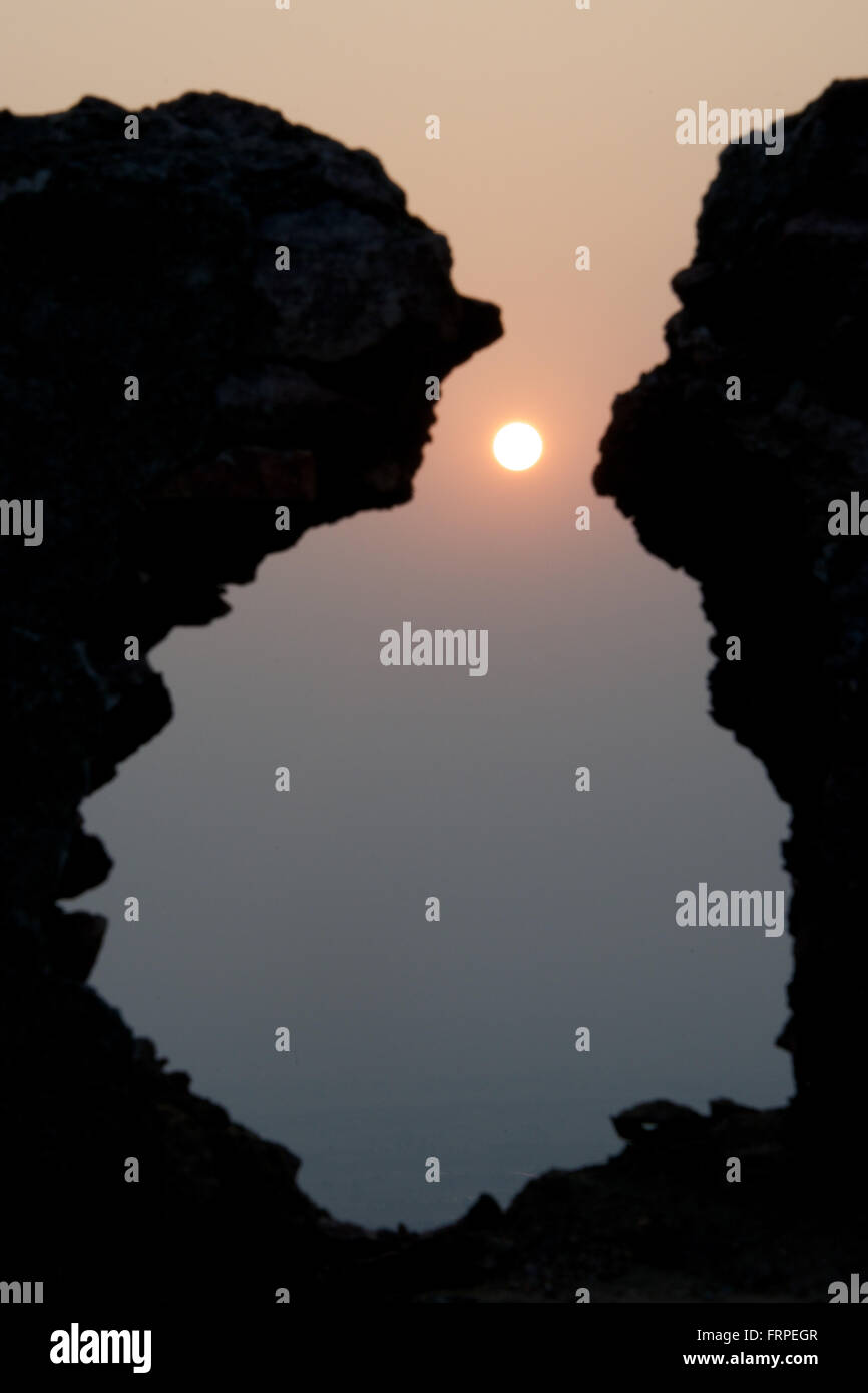 Rising sun through hole in wall Stock Photo - Alamy