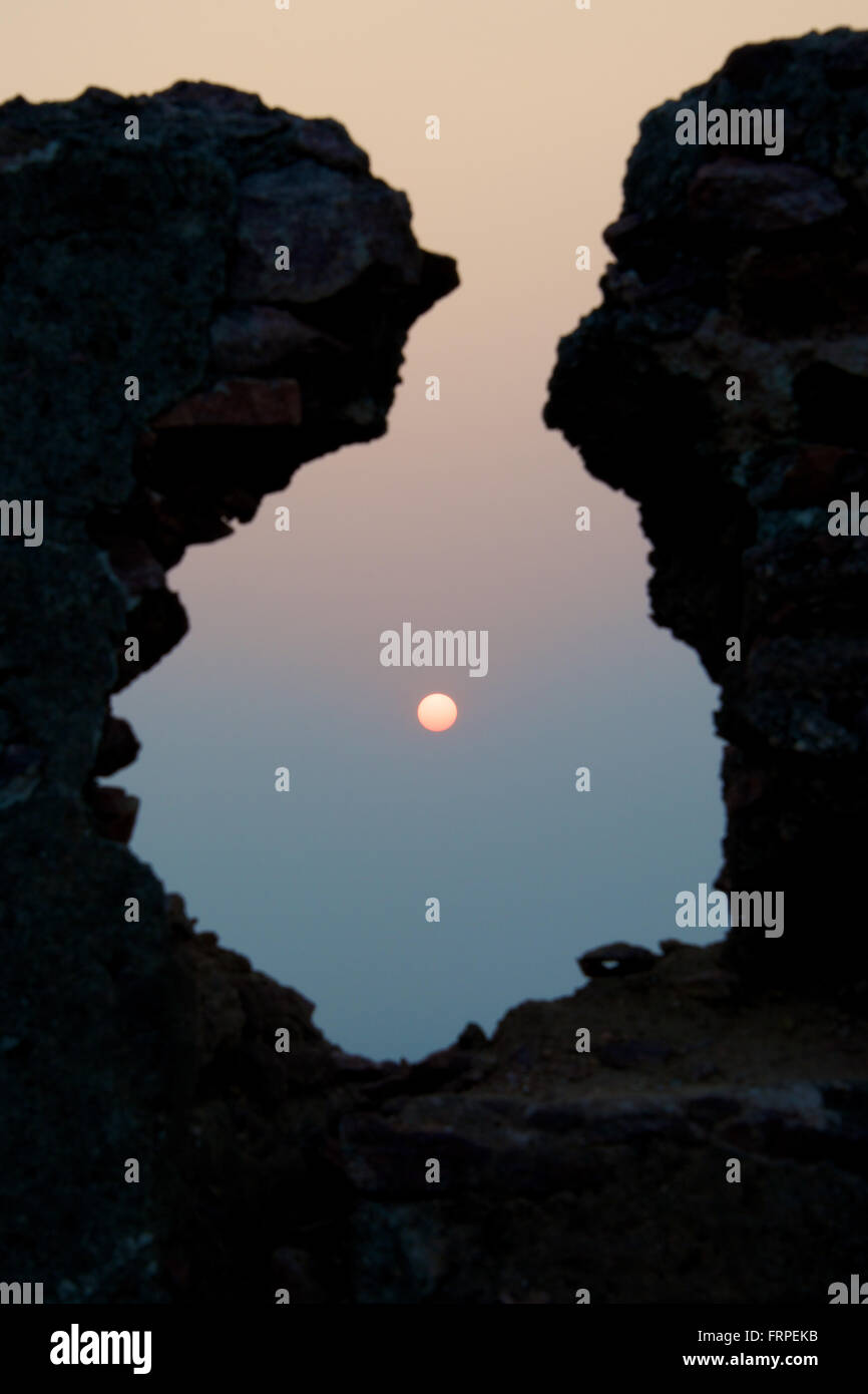 Sun rising through hole in wall Stock Photo - Alamy