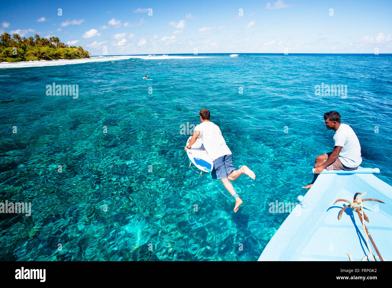 A surfer jumps off a boat with his surfboard Stock Photo - Alamy