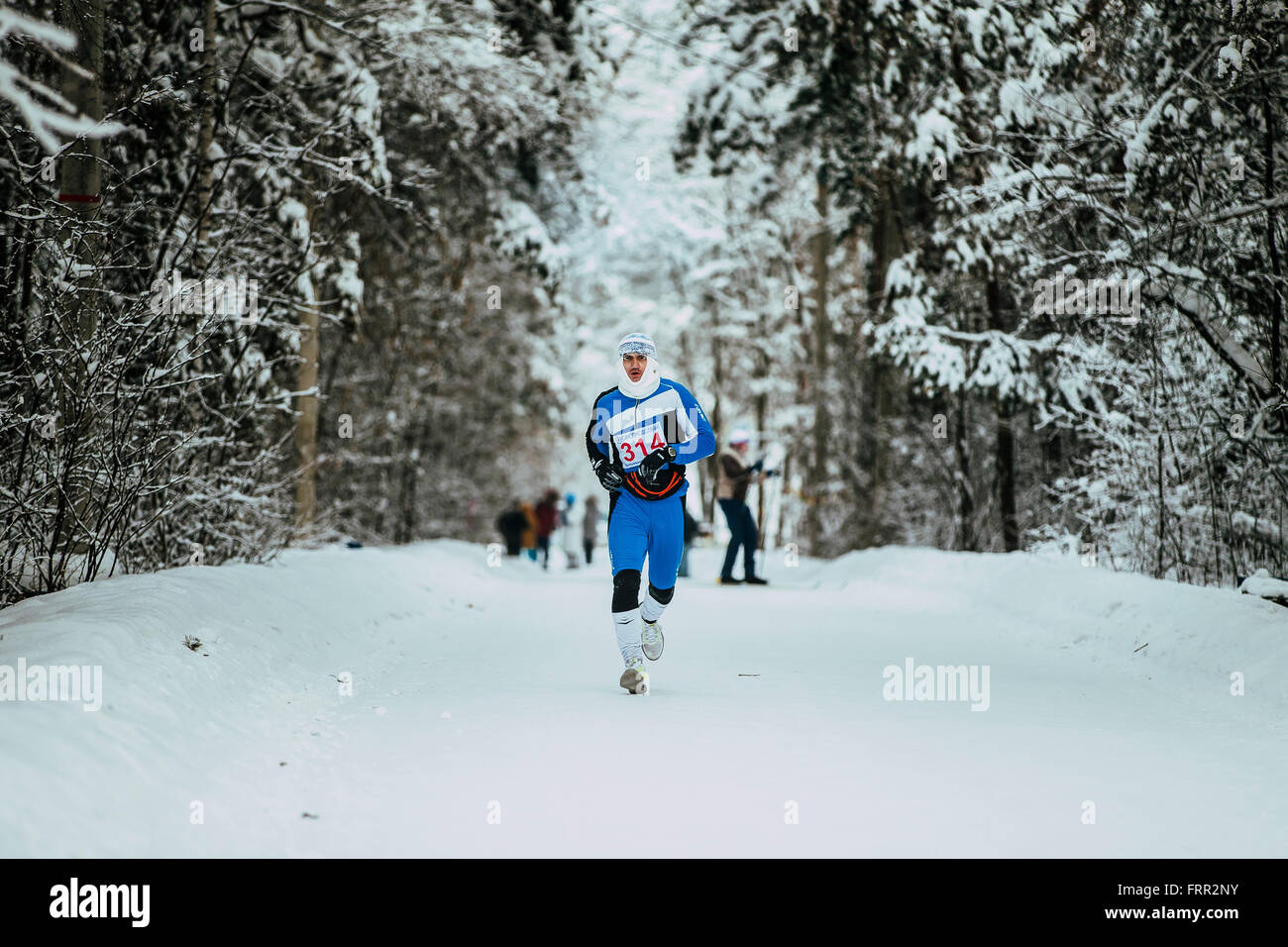 General plan winter forest and young athlete running in cold weather ...