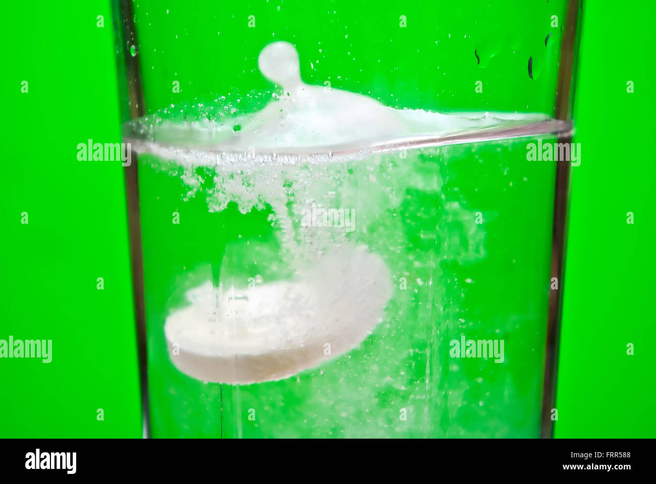 Effervescent tablet dissolving in water on green background Stock Photo ...