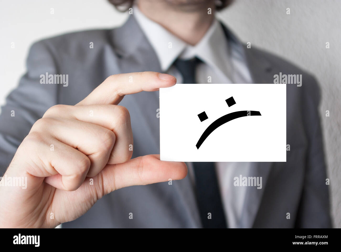 Businessman holding or showing card with a sad smiley face Stock Photo ...