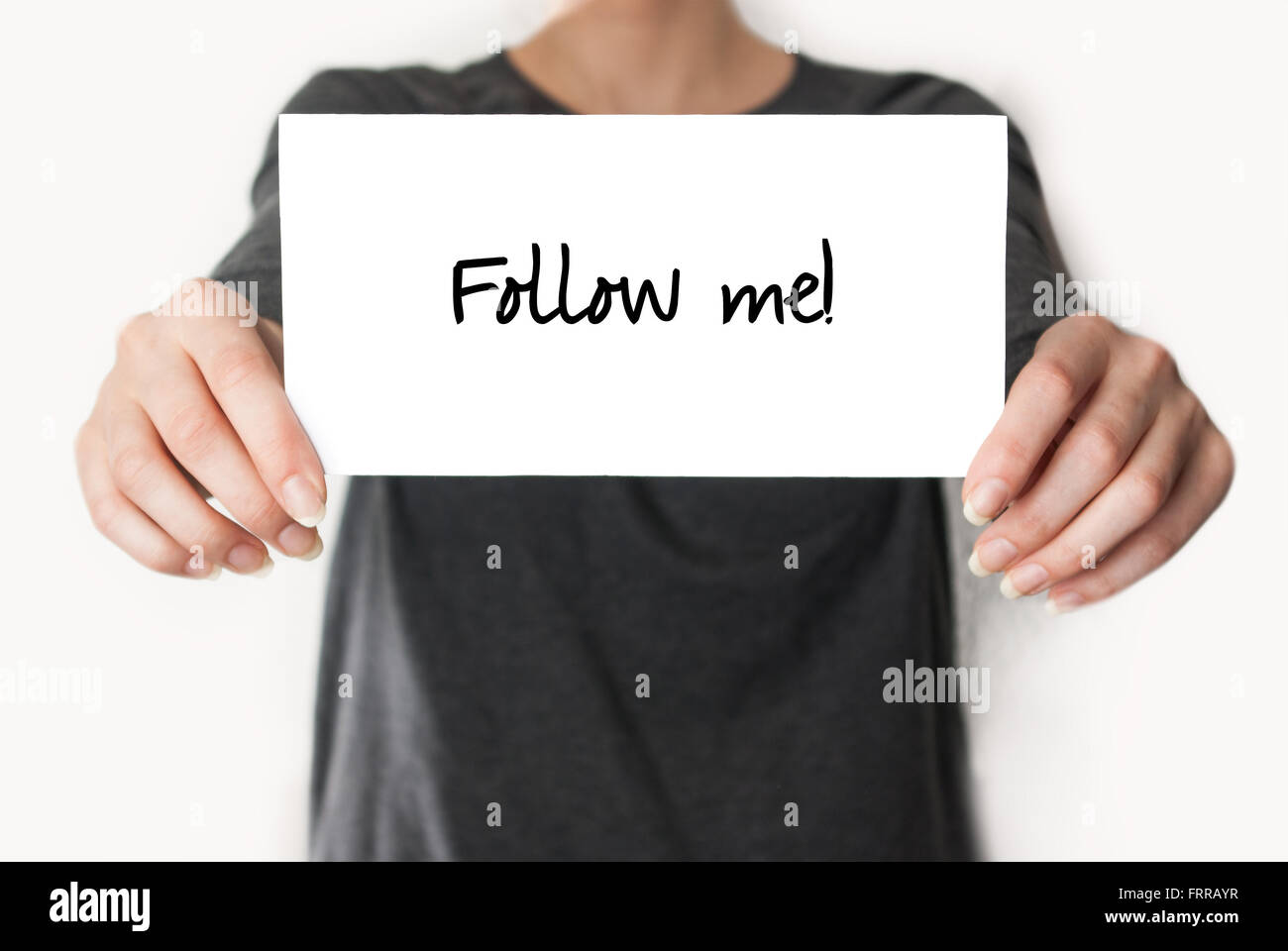 Girl showing or holding card with text follow me Stock Photo - Alamy