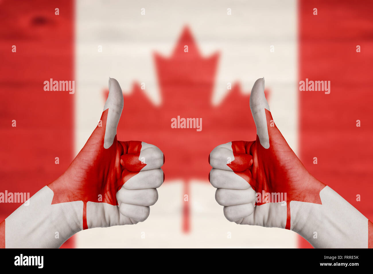Canada flag painted on female hands thumbs up with blurry wooden ...