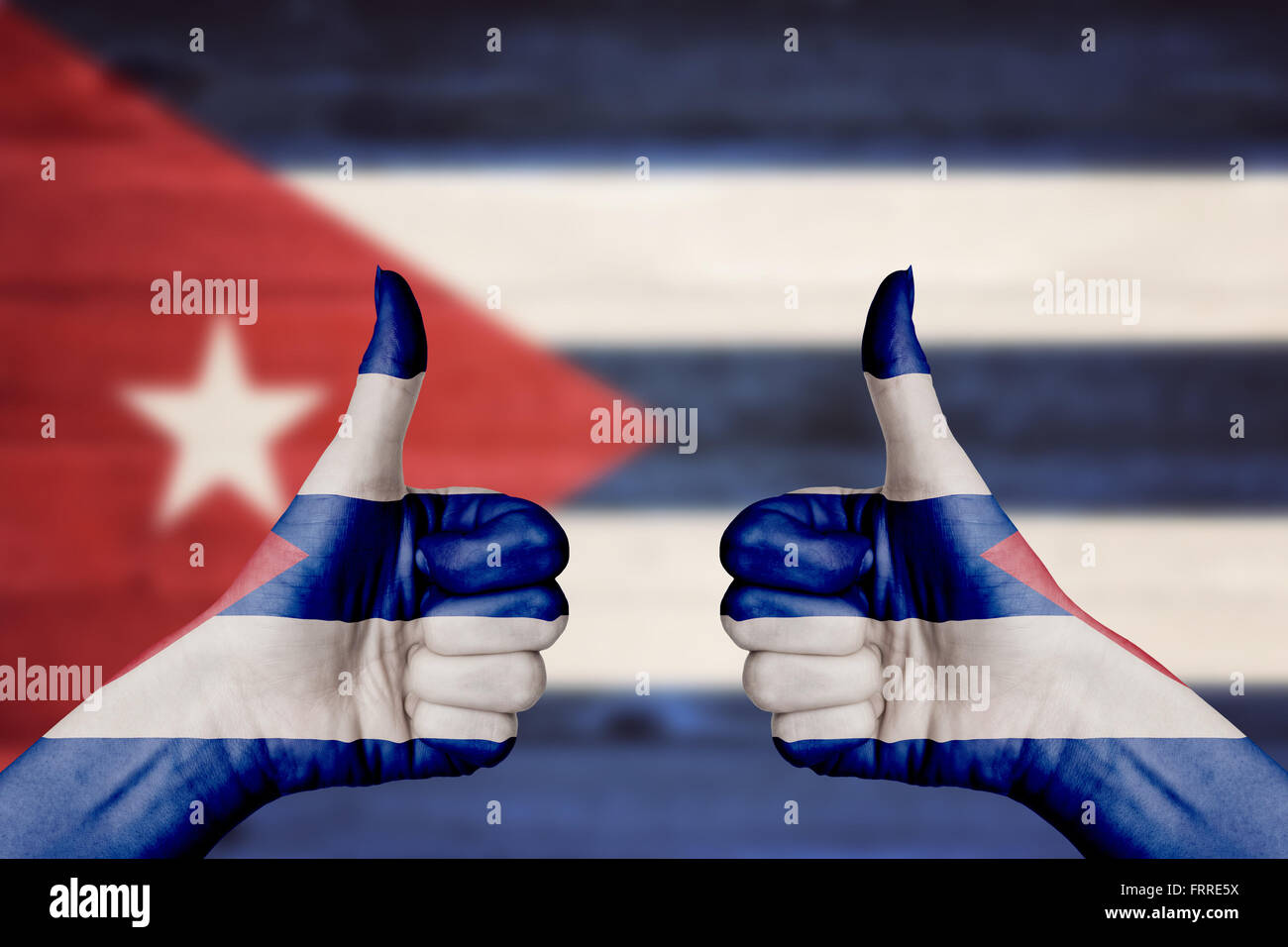 Cuba flag painted on female hands thumbs up with blurry wooden ...