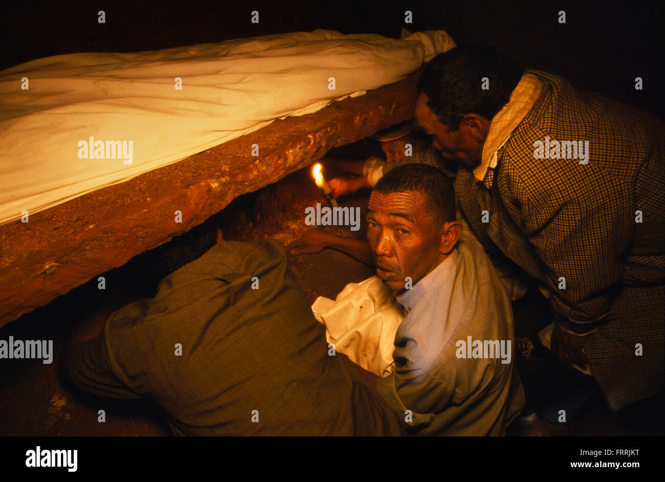 Male members of a family check the remains of the dead inside a grave ...